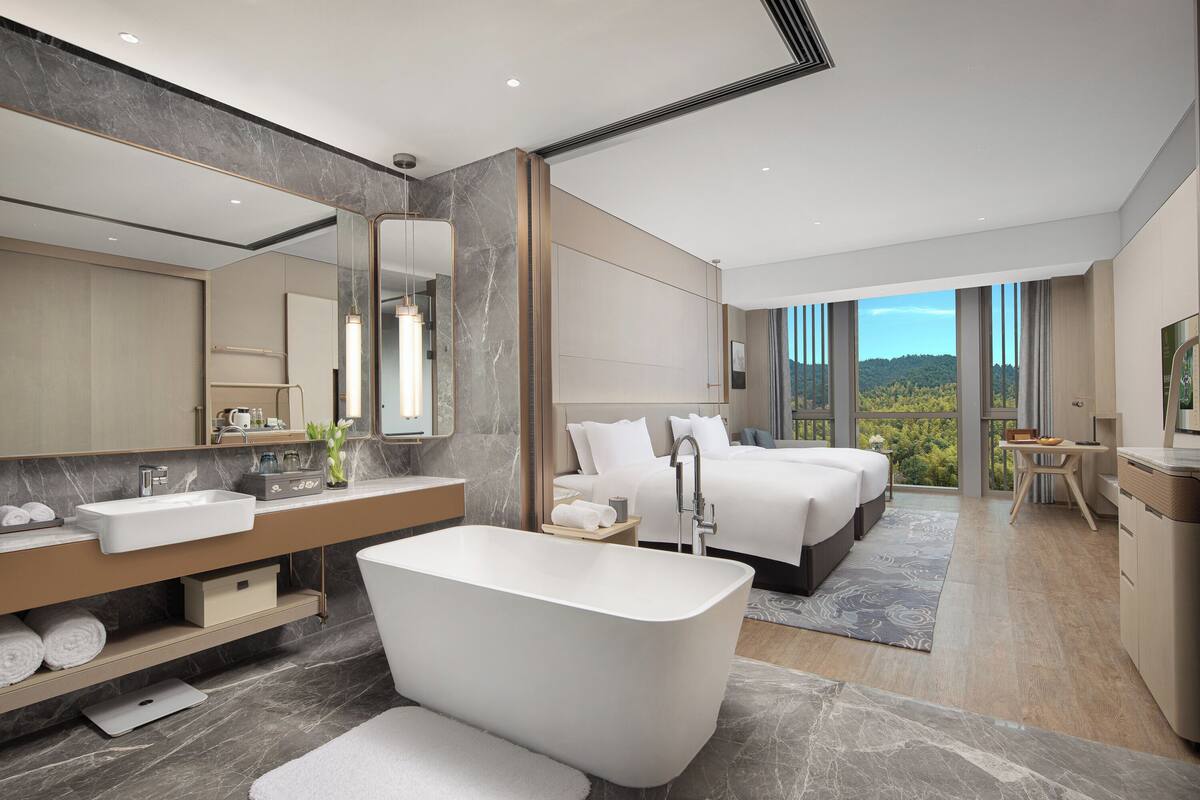 Um banheiro de hotel moderno com uma banheira independente, um espelho grande e um lavatório com pia.