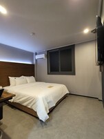 Quarto moderno com cama, escrivaninha e televisão de tela plana.
