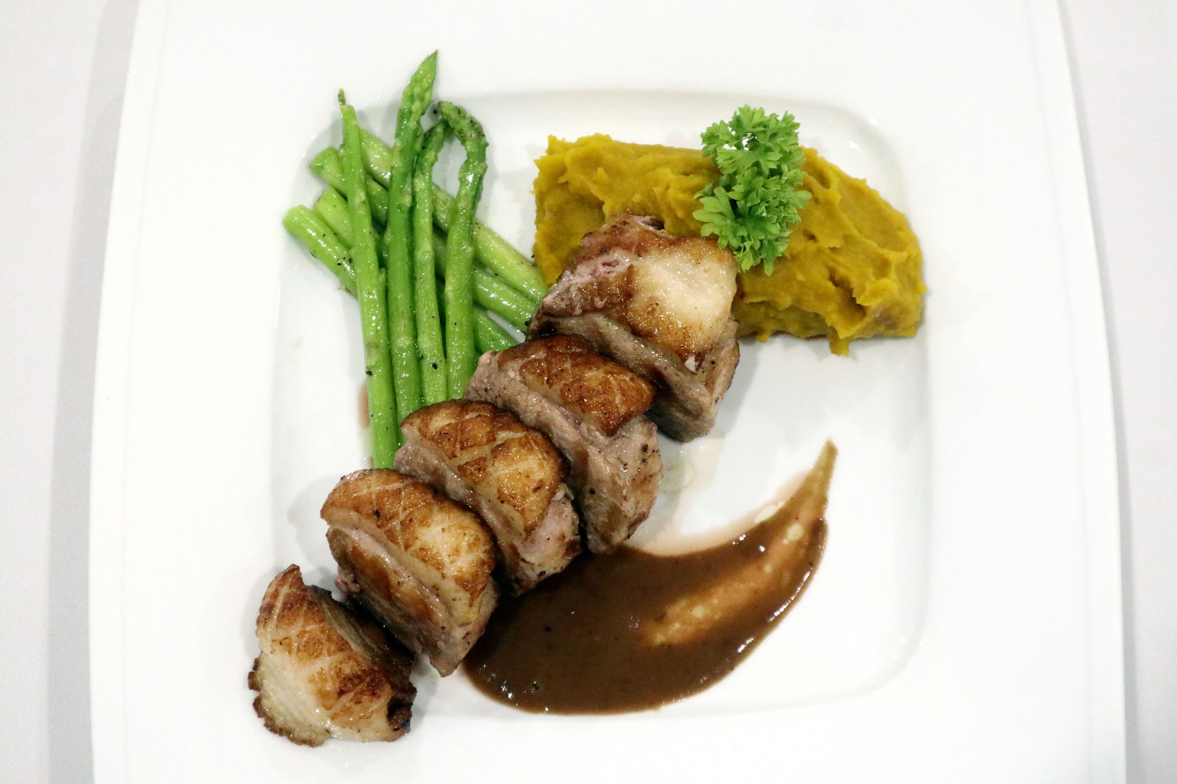 Prato com carne fatiada, vagem, purê de batata e guarnição.