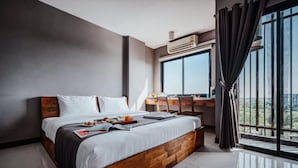Quarto de hotel moderno com uma cama grande, uma escrivaninha e vista para o exterior.