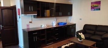 Um espaço compacto com cozinha compacta, sofá e uma pequena mesa com um vaso de flores.
