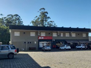 Um edifício com uma placa que diz 'Pousada Choppão' e vários carros estacionados na frente.