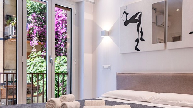 Quarto com cama, almofadas e toalhas dobradas.