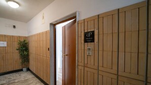 Corredor de hotel com painéis de madeira, um vaso de planta, uma porta com a inscrição 'Abba Rooms' e piso de mármore.