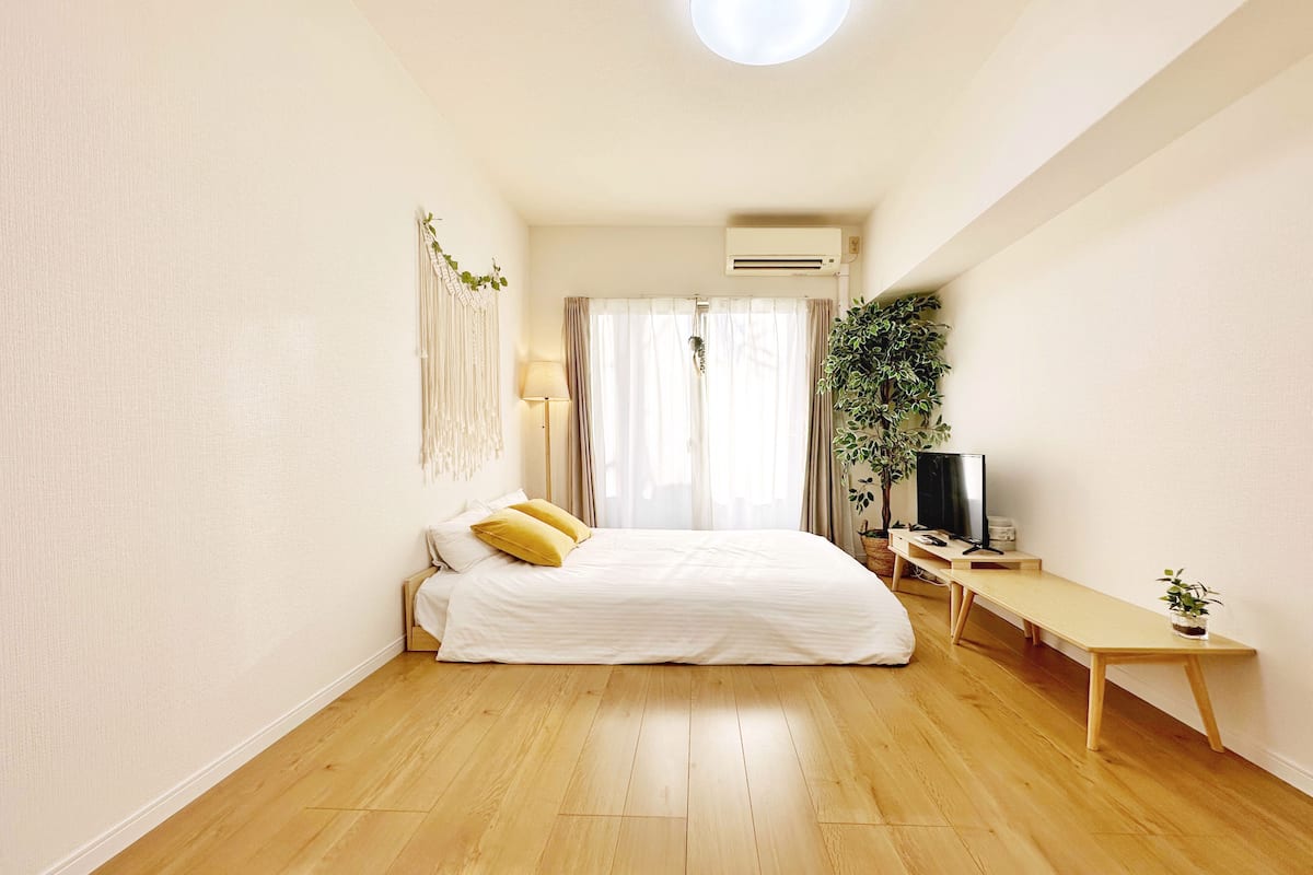 Quarto com cama, televisão, escrivaninha e planta.