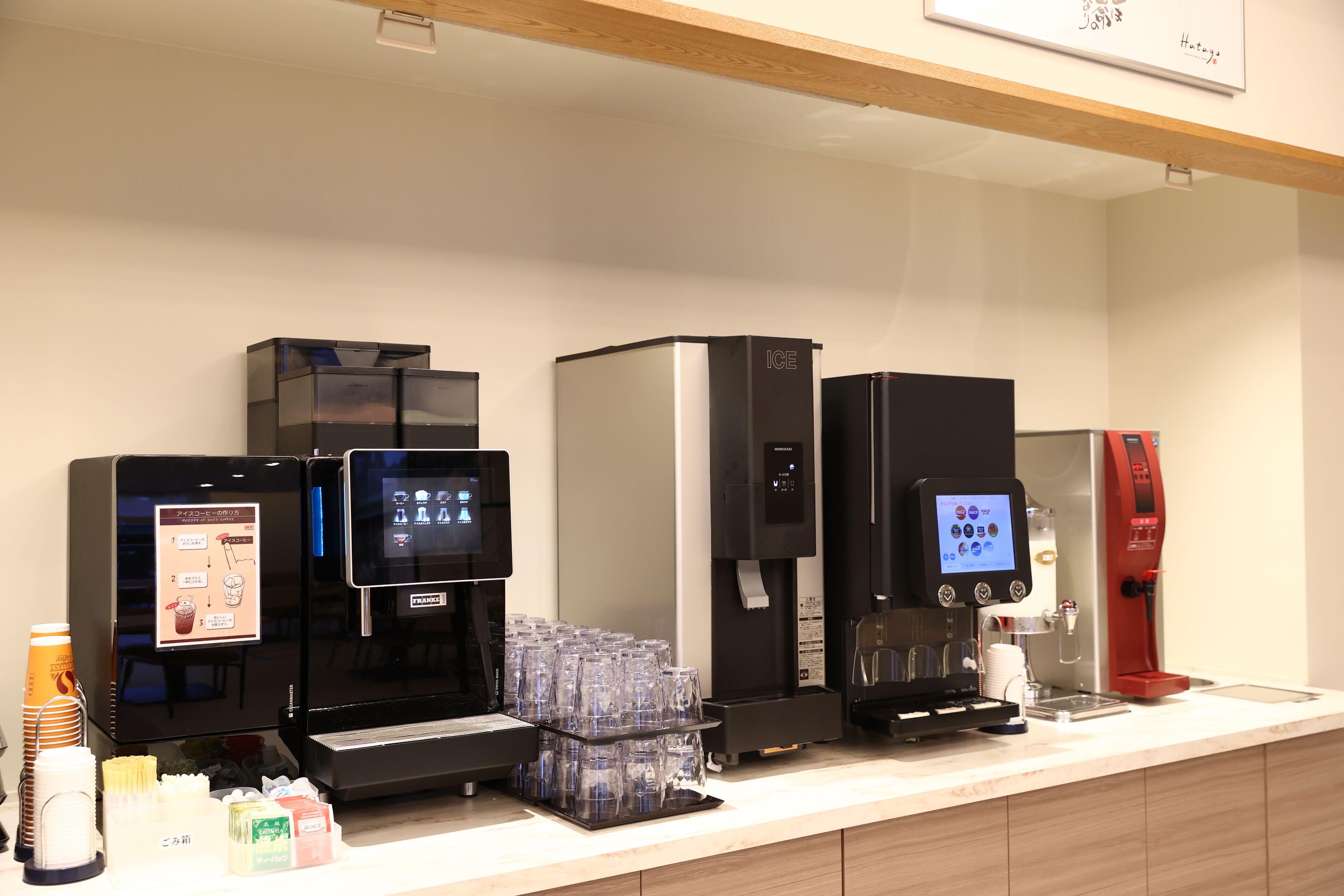 Uma estação de café com várias máquinas de café, um dispensador de água e um dispensador de bebidas vermelho.