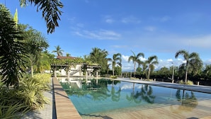 Piscina com deck de madeira e plantas tropicais.