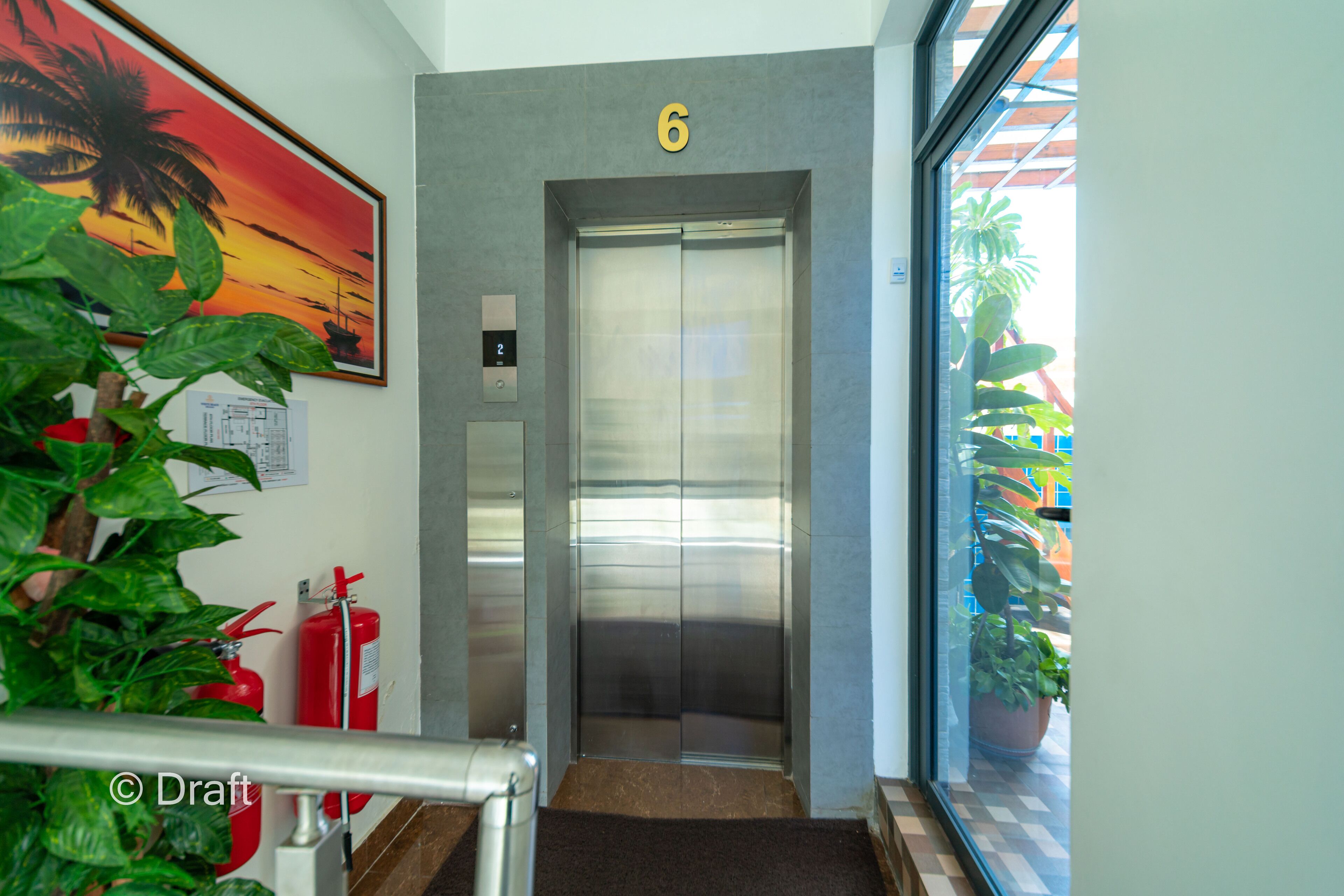 Um elevador com uma placa indicando o número 6, um extintor de incêndio e uma planta em vaso perto da entrada.