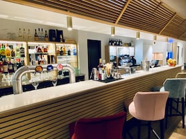 Uma área de bar com balcão, diversas torneiras e uma variedade de garrafas e copos.