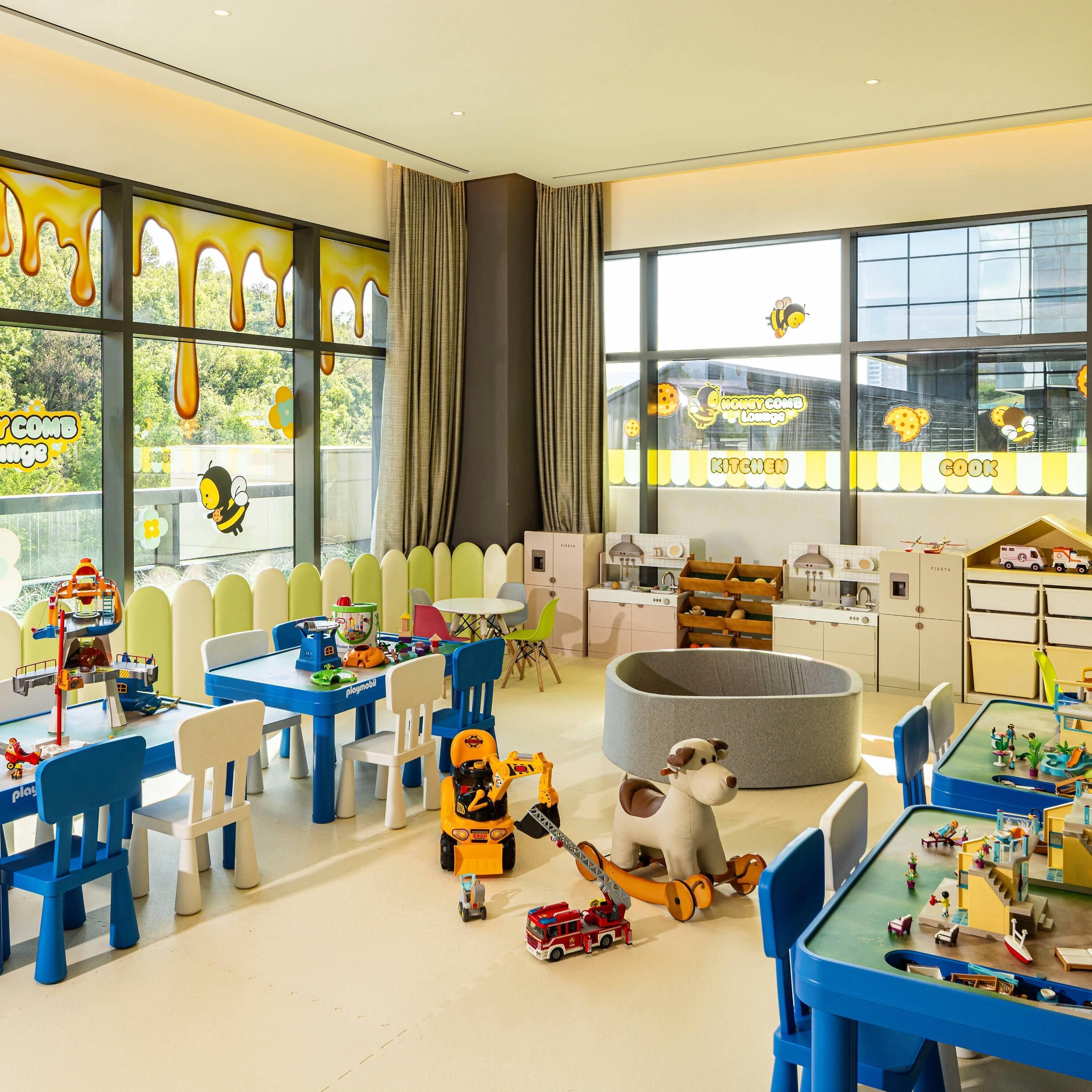 Uma área de recreação infantil com mesas, cadeiras e diversos brinquedos.