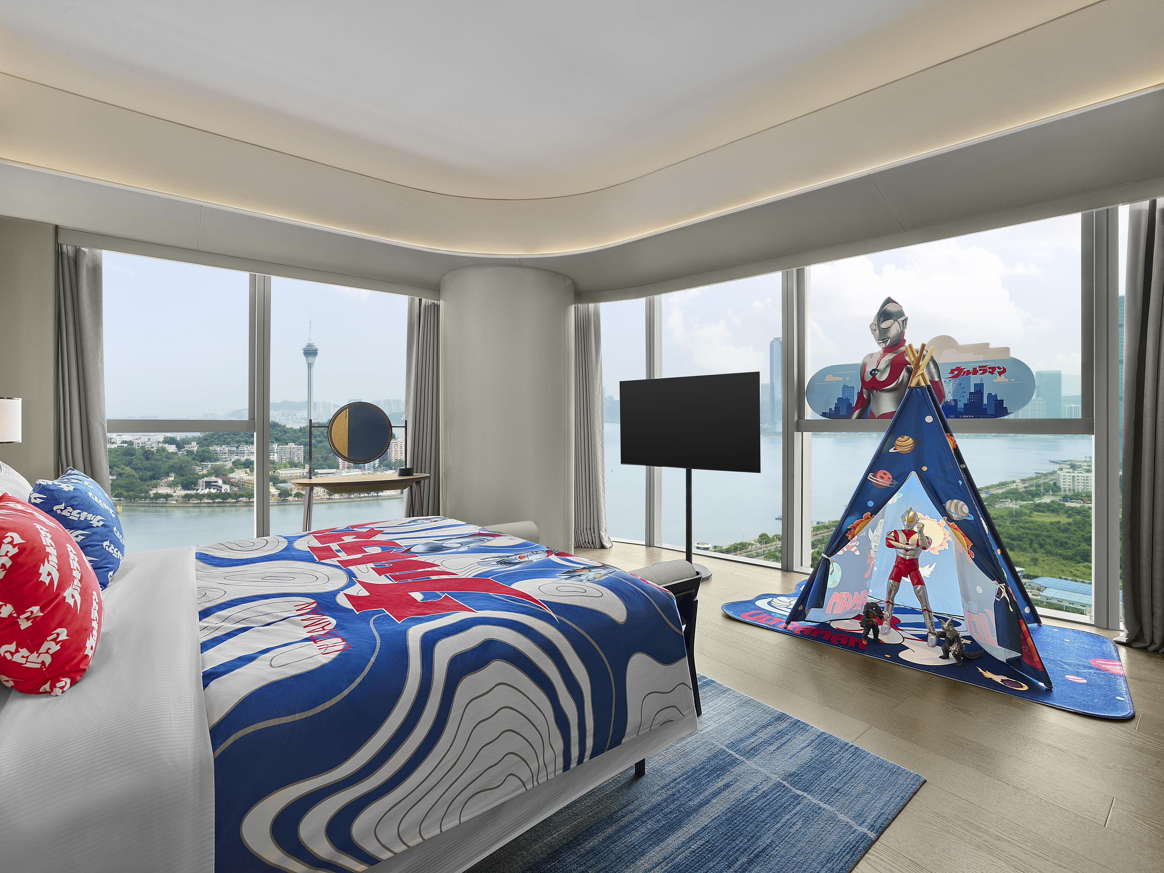 Quarto de hotel com cama grande, televisão, vista para a cidade e decoração com tendas.