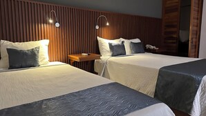 Quarto de hotel com duas camas, painéis de madeira nas paredes e luminárias de cabeceira.