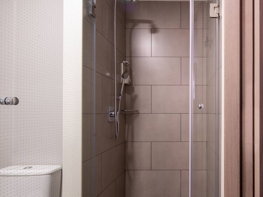 Uma casa de banho moderna com chuveiro em vidro, sanita e lavatório.