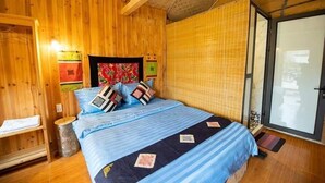 Um quarto de madeira com uma cama, uma mesinha e uma porta de vidro deslizante.