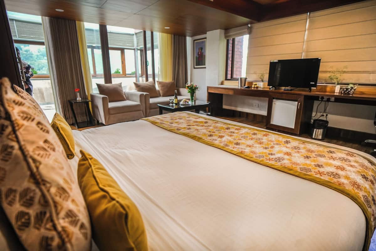 Quarto de hotel com uma cama grande, uma escrivaninha, uma televisão e vista para o exterior.