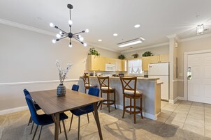 Uma cozinha moderna com ilha central, cadeiras de madeira e uma mesa de jantar.