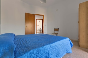 Quarto com uma cama grande, um guarda-roupa de madeira e uma porta que dá para um banheiro.