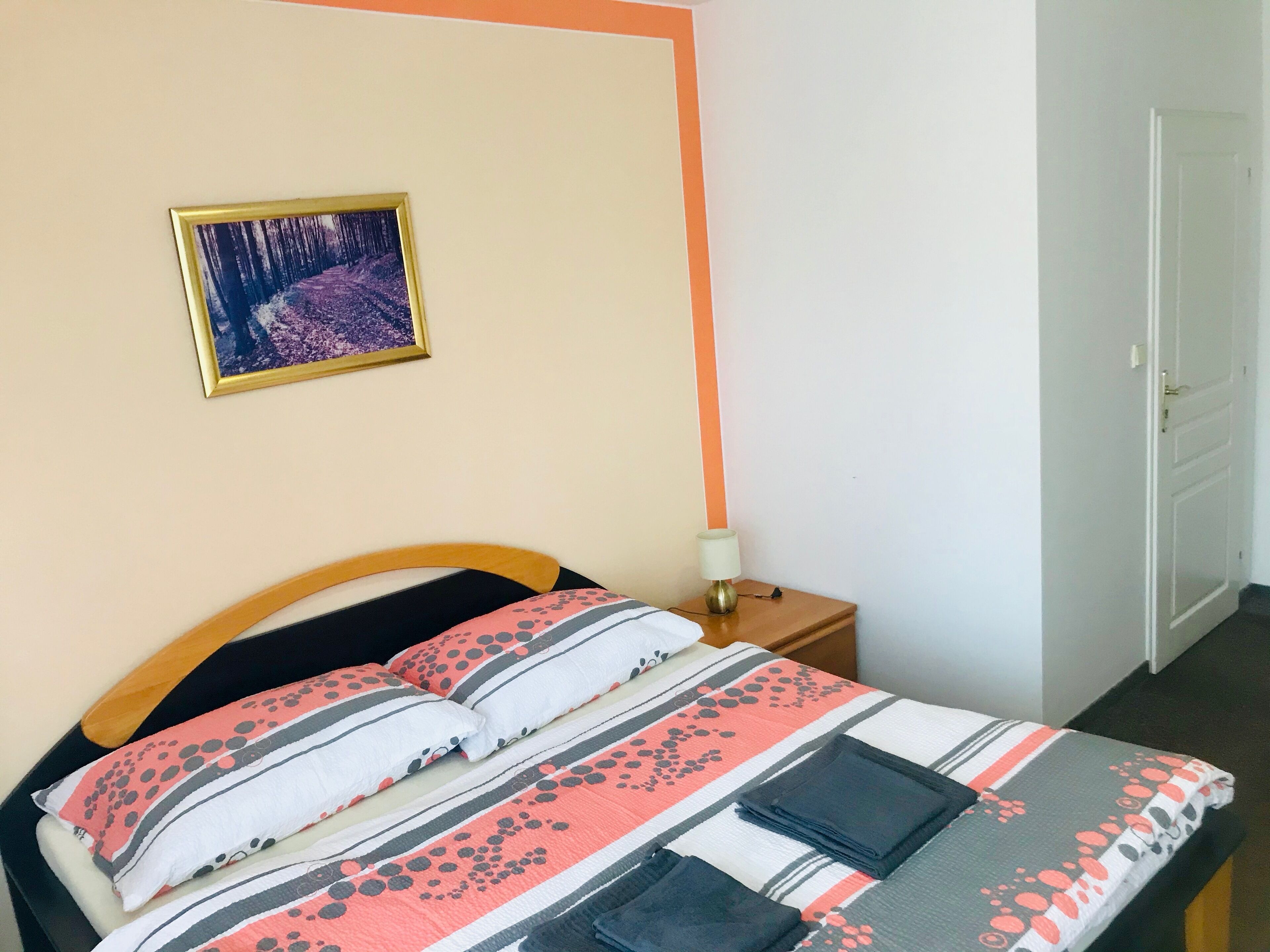 Uma cama bem arrumada com colcha listrada, um abajur e um quadro na parede.