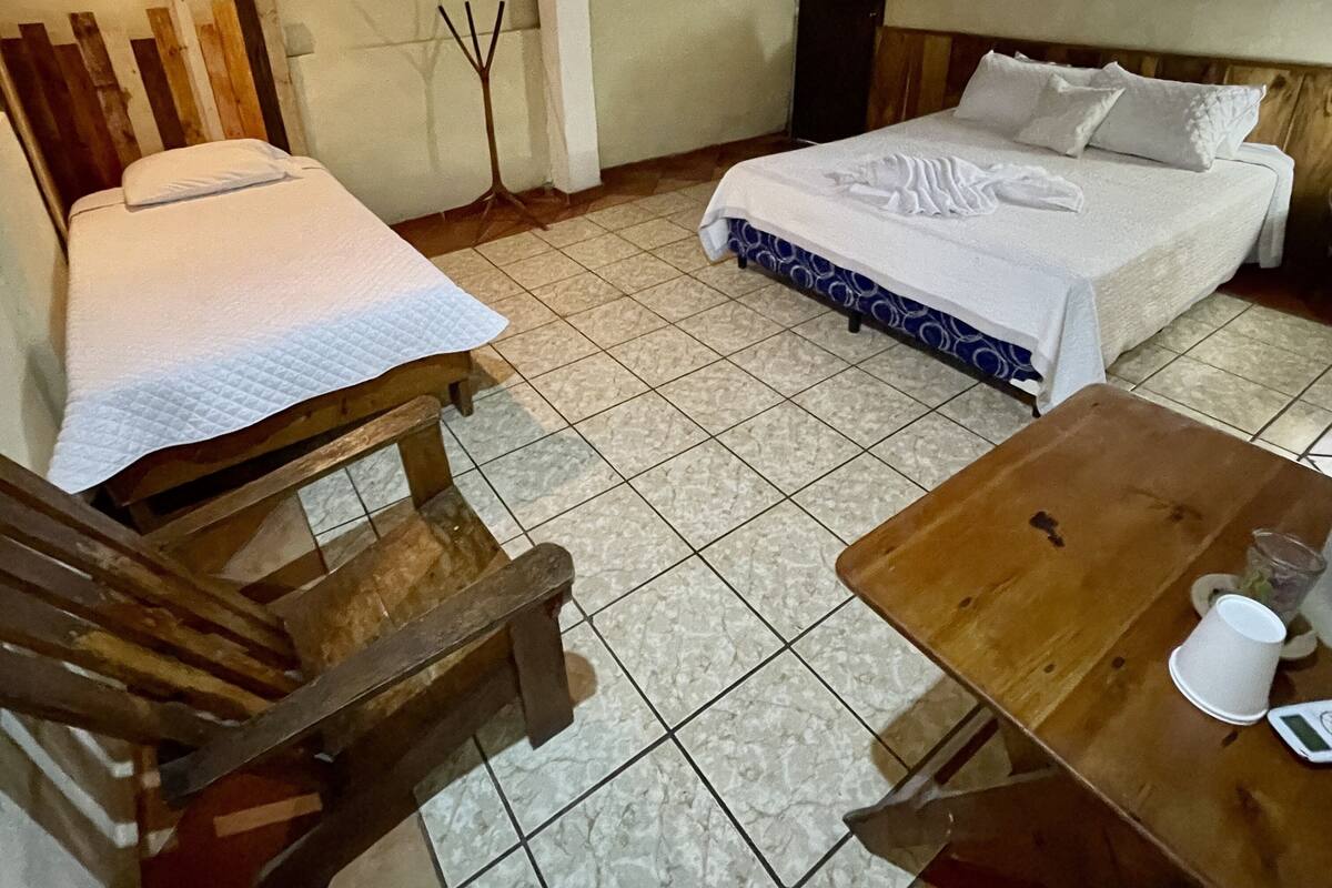 Quarto com duas camas, uma mesa de madeira e uma cadeira.