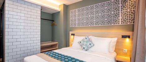 Quarto de hotel moderno com uma cama bem arrumada, um painel decorativo fixado na parede e uma mesa de cabeceira com luminária.