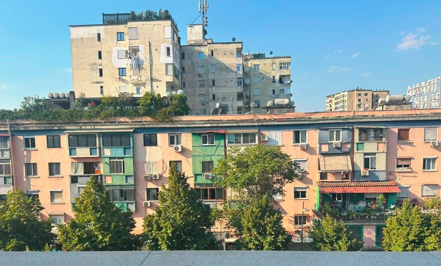 Um edifício residencial de vários andares, com varandas, aparelhos de ar condicionado e um céu claro.