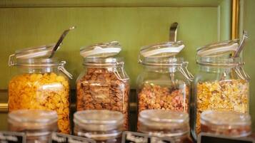 Quatro potes de vidro com tampas de metal, cada um contendo diferentes tipos de granola ou cereal.