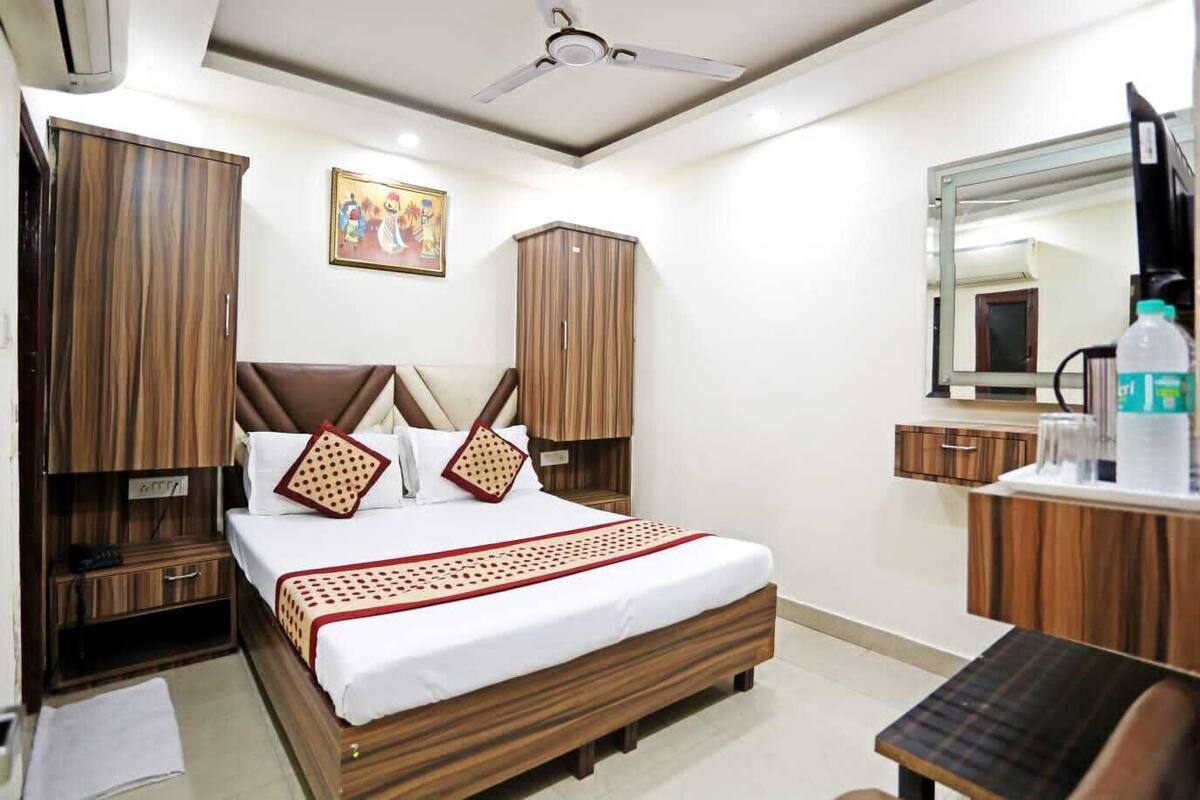 Quarto de hotel com cama, guarda-roupa, escrivaninha e espelho.