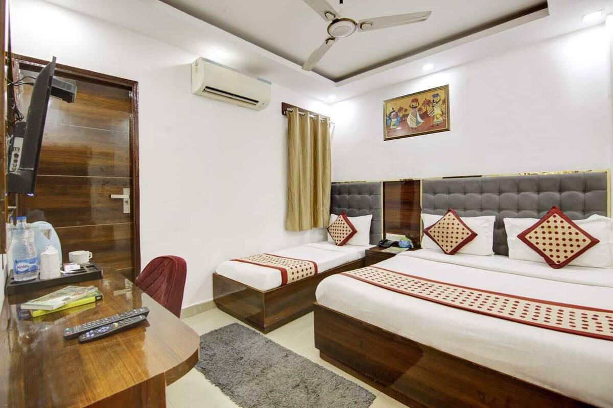 Quarto de hotel com cama, escrivaninha com cadeira, televisão e ar condicionado.