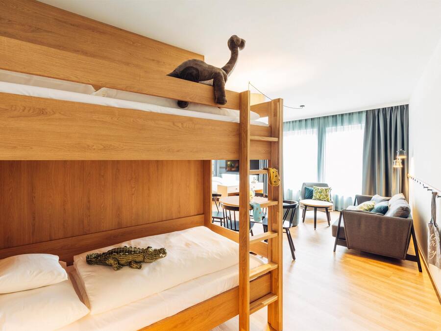 Uma cama beliche com escada, uma mesinha e um sofá numa sala de estar moderna.