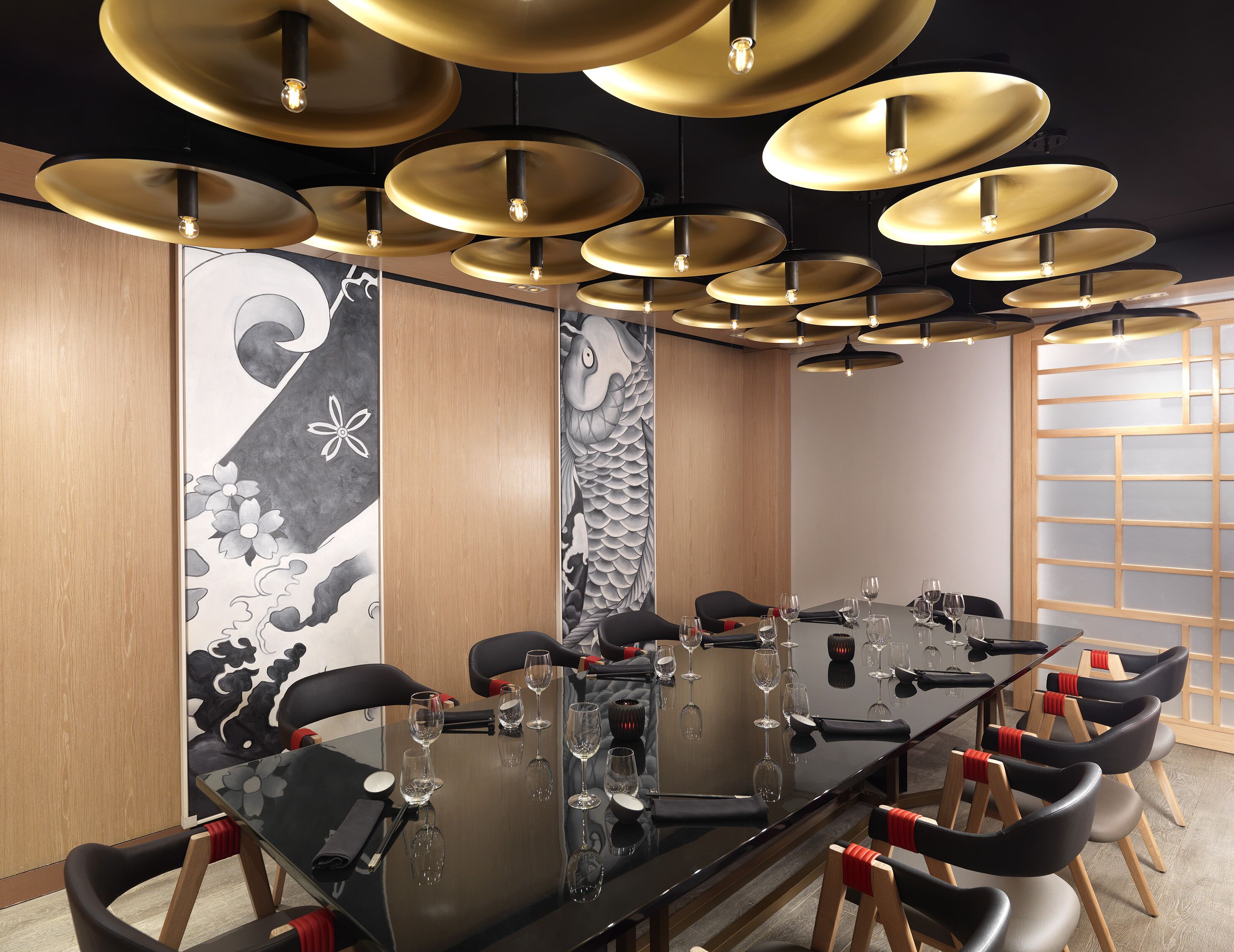 Uma sala de jantar com uma mesa comprida, várias cadeiras e luminárias pendentes.