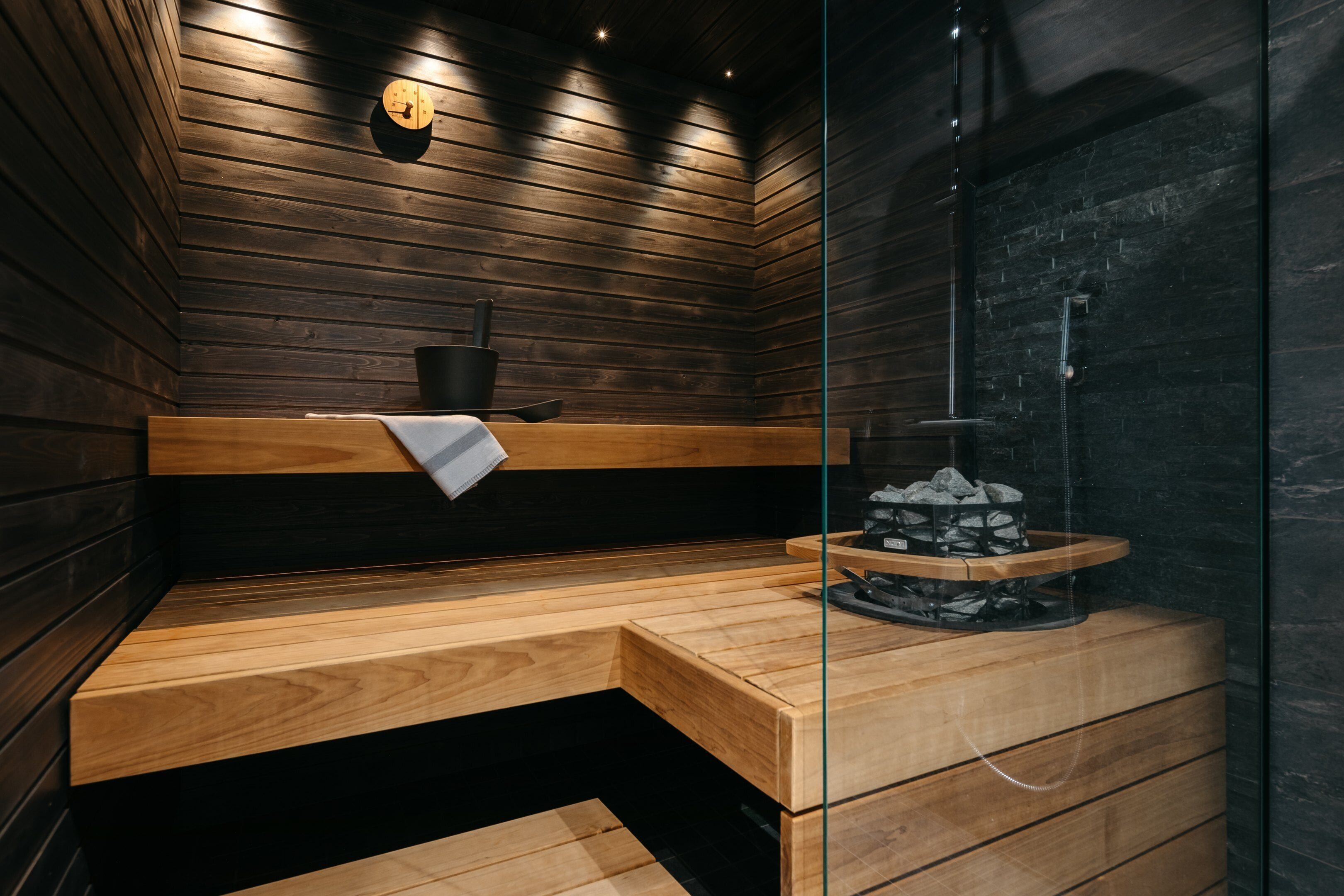 Uma sauna com bancos de madeira, um porta-toalhas e uma bacia de pedra.
