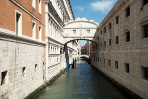 Um canal estreito com edifícios em ambos os lados e uma ponte ao longe.