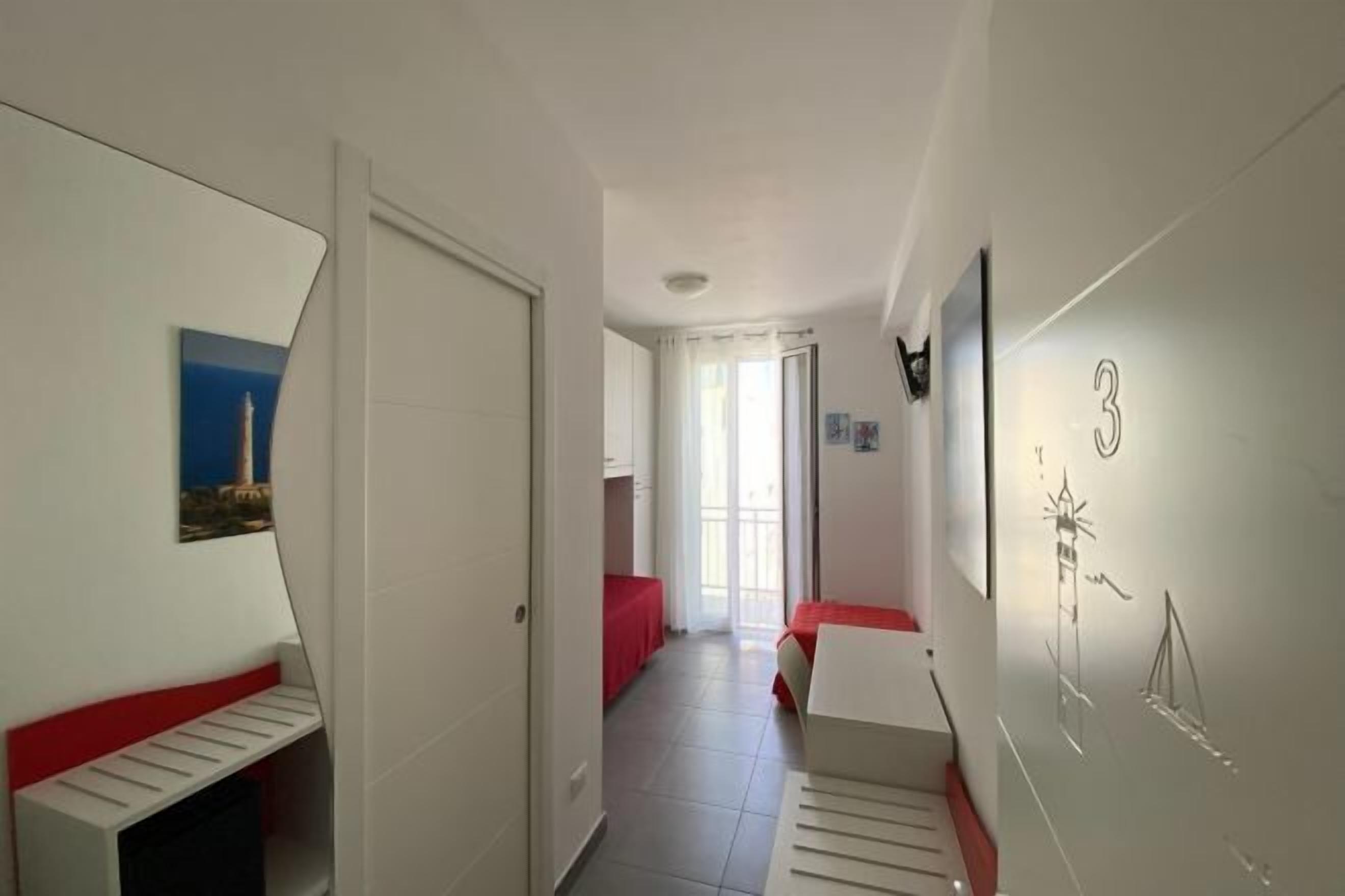 Corredor com uma cama, uma porta e uma parede com um número.