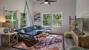 Um quarto aconchegante com uma cadeira suspensa, um sofá e um tapete estampado.