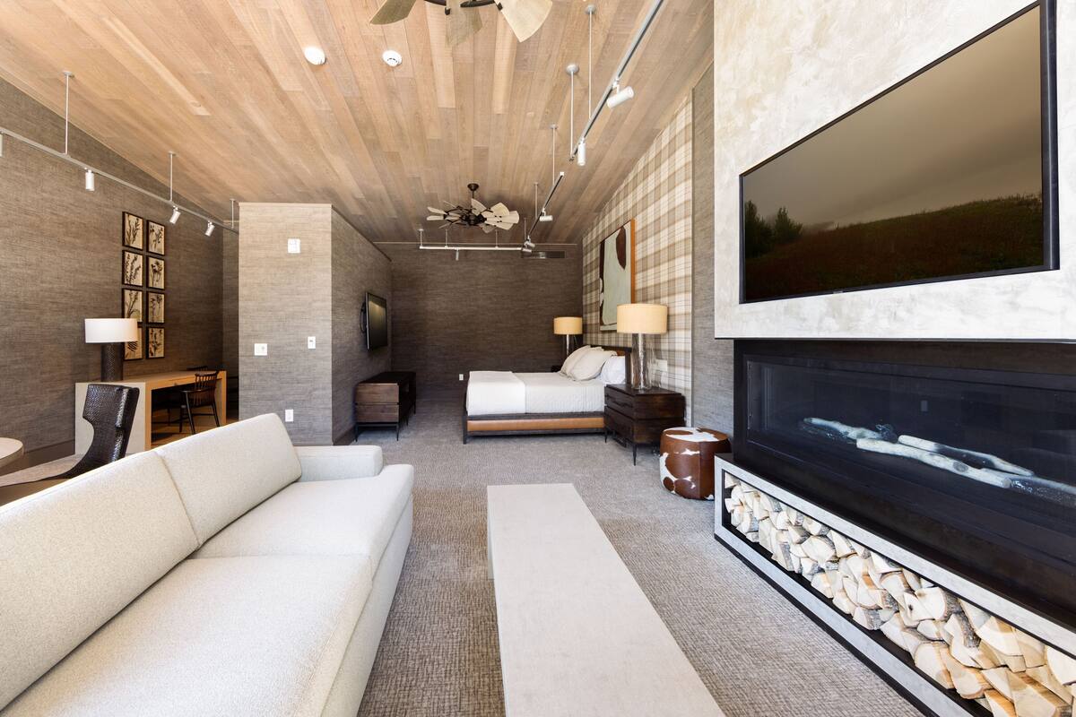 Quarto moderno com uma cama grande, um sofá, uma televisão e uma lareira.