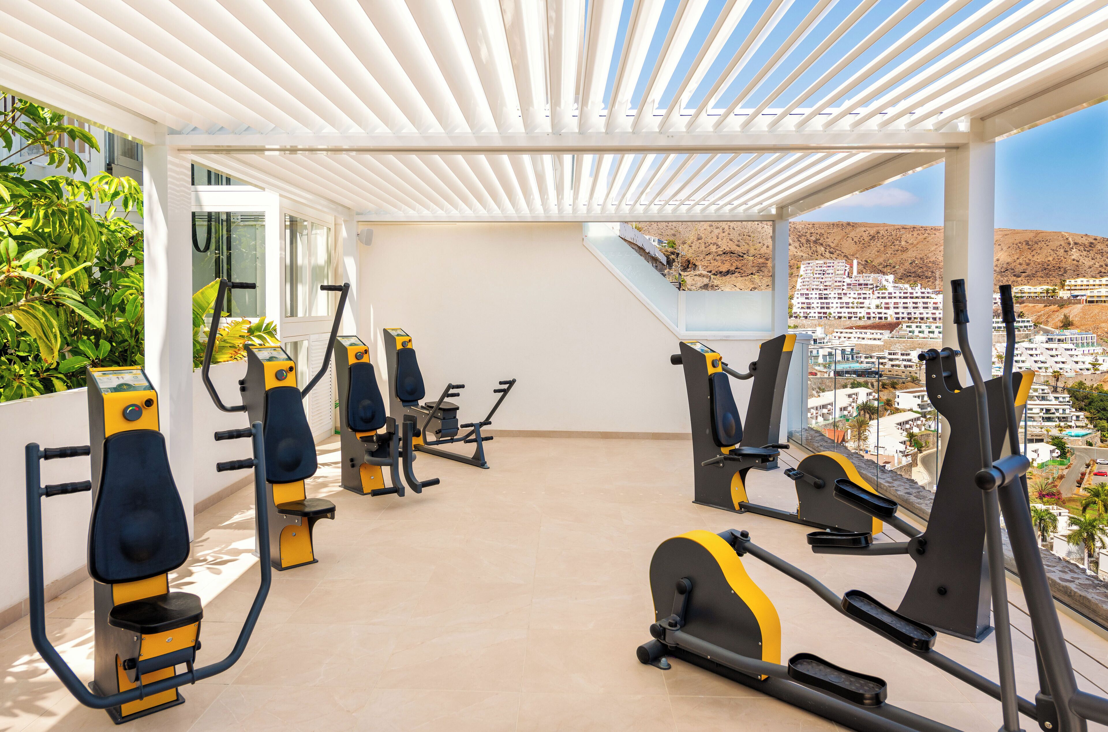 Academia com equipamentos de ginástica e vista para uma cidade costeira.