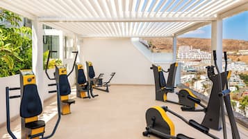 Academia com equipamentos de ginástica e vista para uma cidade costeira.
