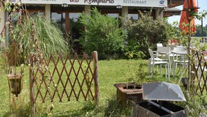 Bar e restaurante chamado "Les Remparts", com mesas ao ar livre e cerca rústica.