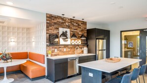 Cozinha moderna com painel de ladrilhos, eletrodomésticos de aço inoxidável e área de refeições com assentos laranja.