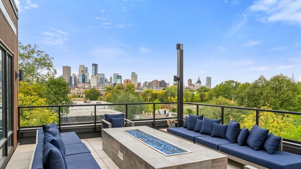 Terraço no telhado com vista para o horizonte urbano, mobiliário externo e lareira moderna.