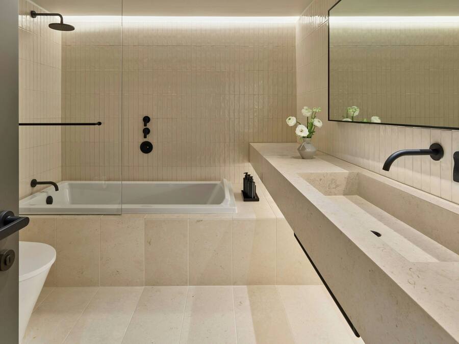 Uma casa de banho moderna com banheira, sanita, lavatório e espelho.