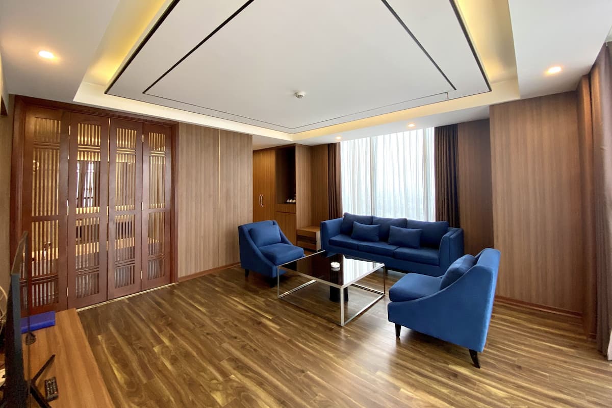 Uma sala de estar moderna com um sofá azul, piso de madeira e iluminação embutida no teto.
