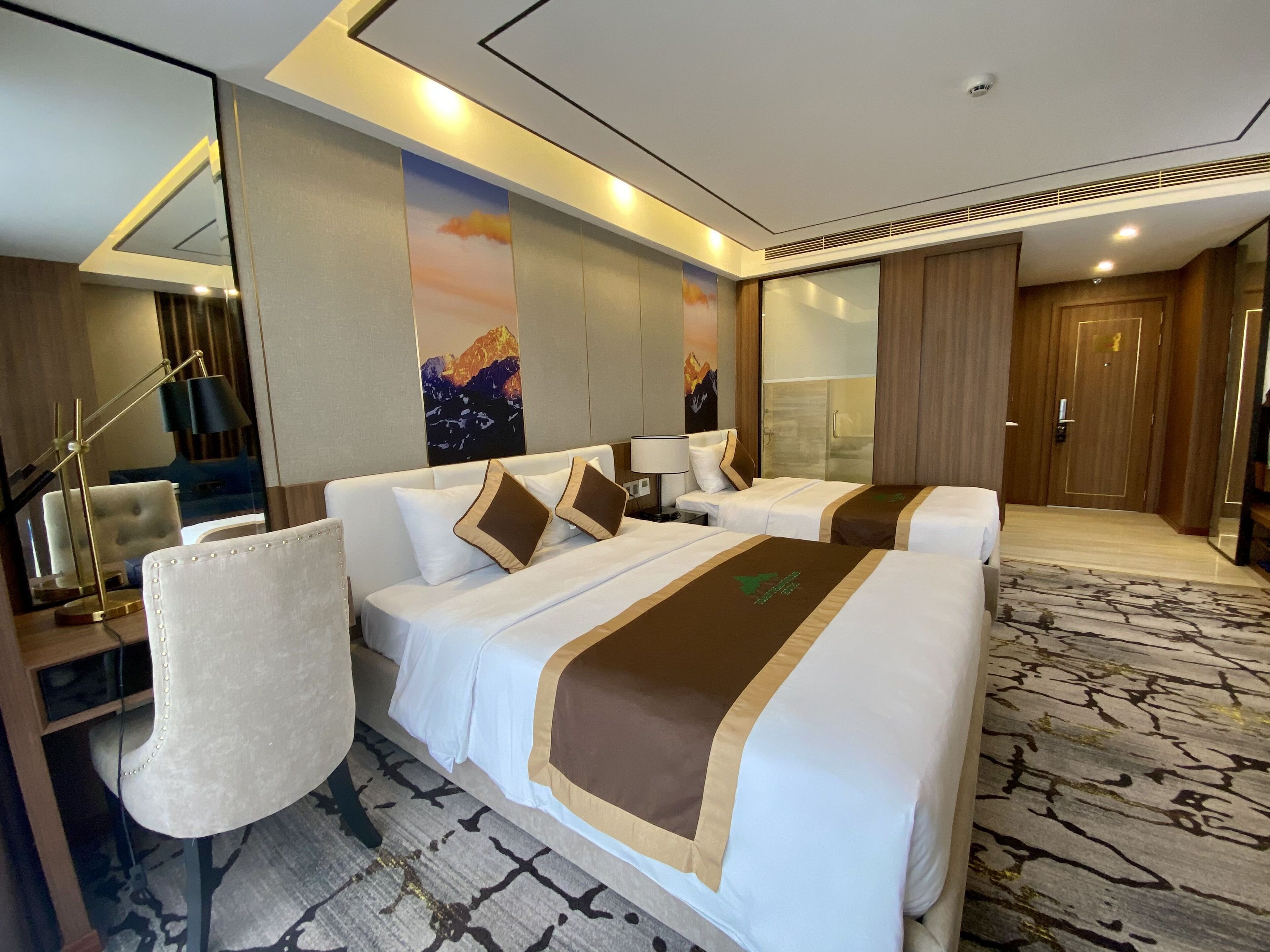 Quarto de hotel com uma cama grande, um sofá, uma cadeira, uma escrivaninha e um espelho.