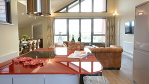 Cozinha moderna com ilha central, sala de jantar com mesa e cadeiras, e uma grande janela que proporciona iluminação natural.