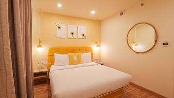 Quarto de hotel com cama, mesas de cabeceira, espelho e quadros nas paredes.
