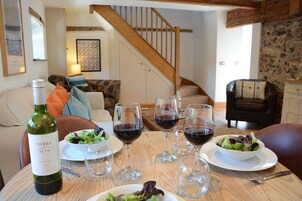 Uma mesa de jantar com copos de vinho, garrafa de vinho e pratos de comida.