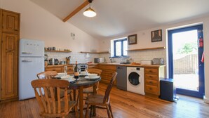 Uma cozinha com armários de madeira, máquina de lavar embutida e área de jantar com cadeiras e mesa de madeira.