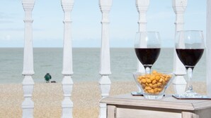 Varanda com balaústres brancos com vista para uma praia.