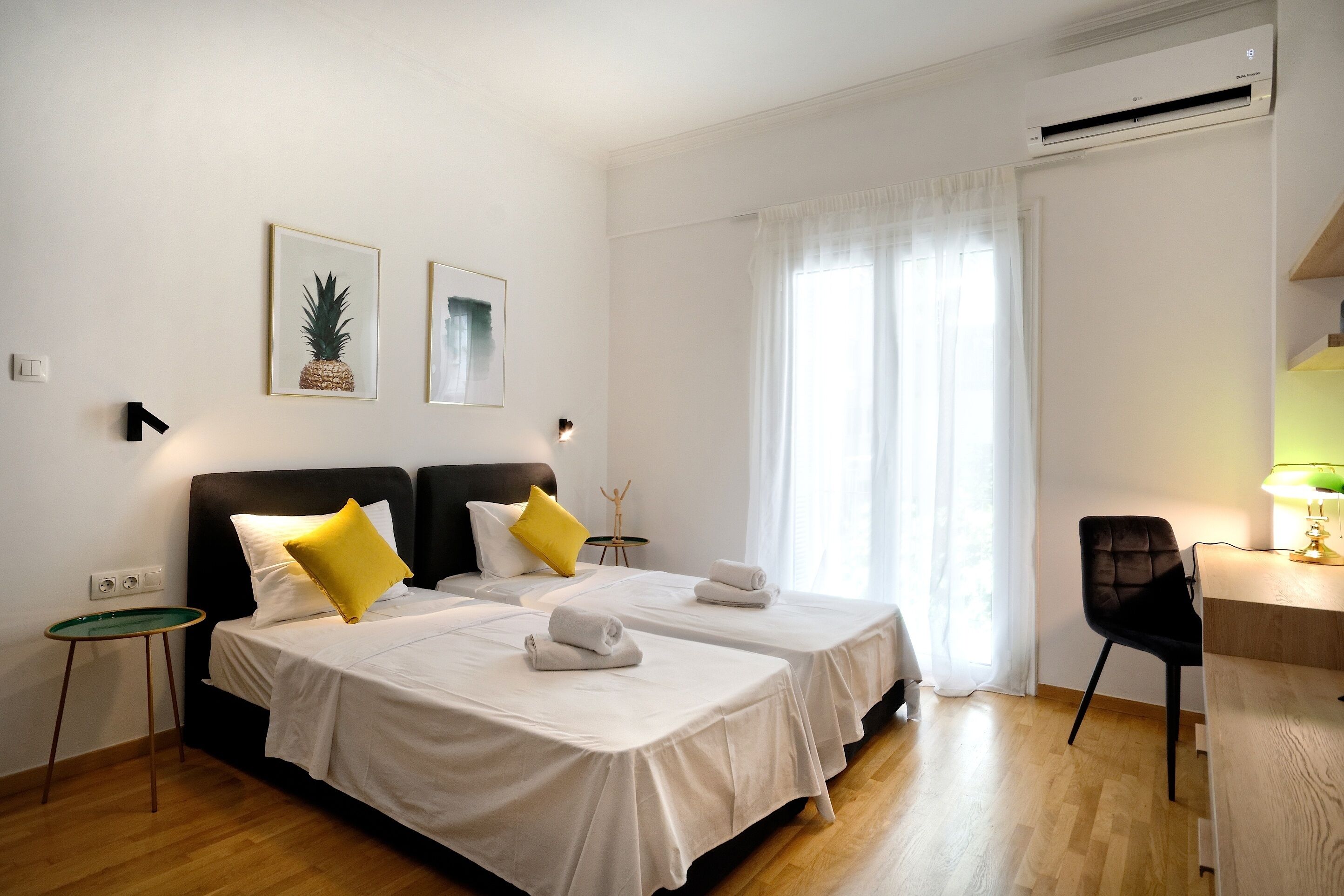 Quarto de hotel com duas camas, uma escrivaninha e uma cadeira.