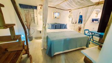 Quarto com cama, escrivaninha, cadeira, luminária pendente e um vaso com galhos.
